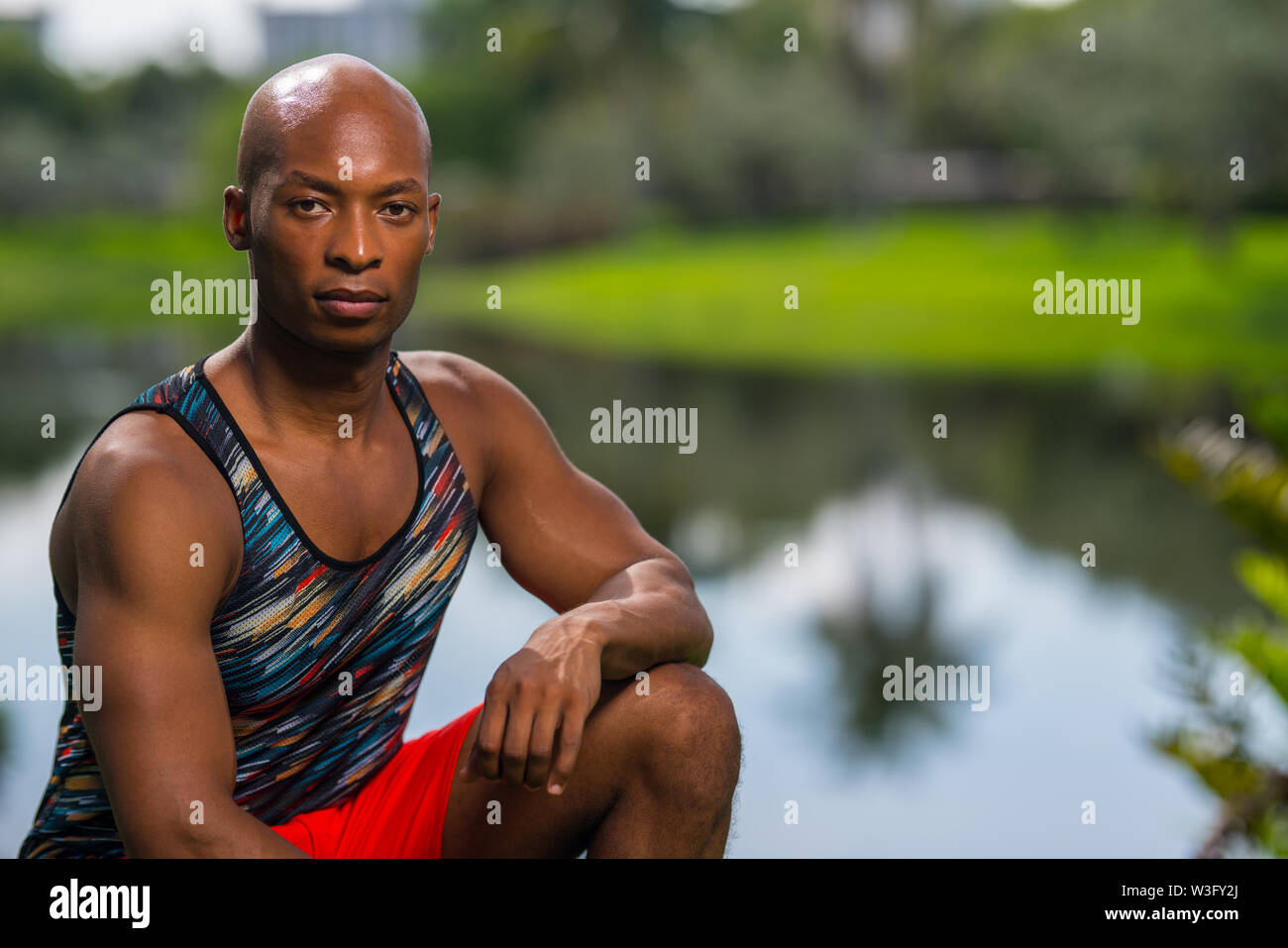 Portrait of a man squatting with dead pan expression. Image lit with ...