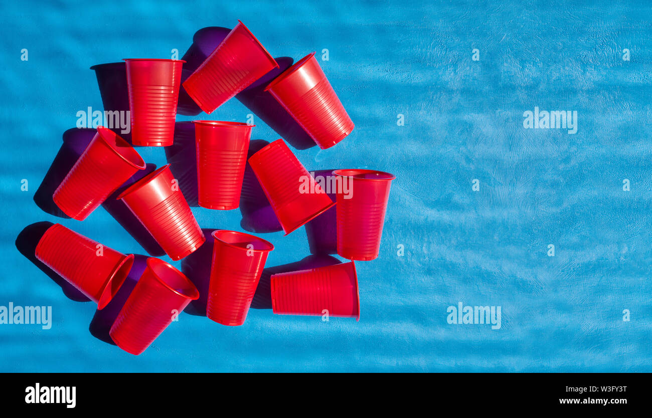 Glasses disposable from plastic. On the red cups the bright sun shines ...