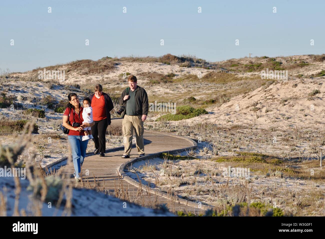 People, mother child, walking on boardwalk pathway through coastal ...