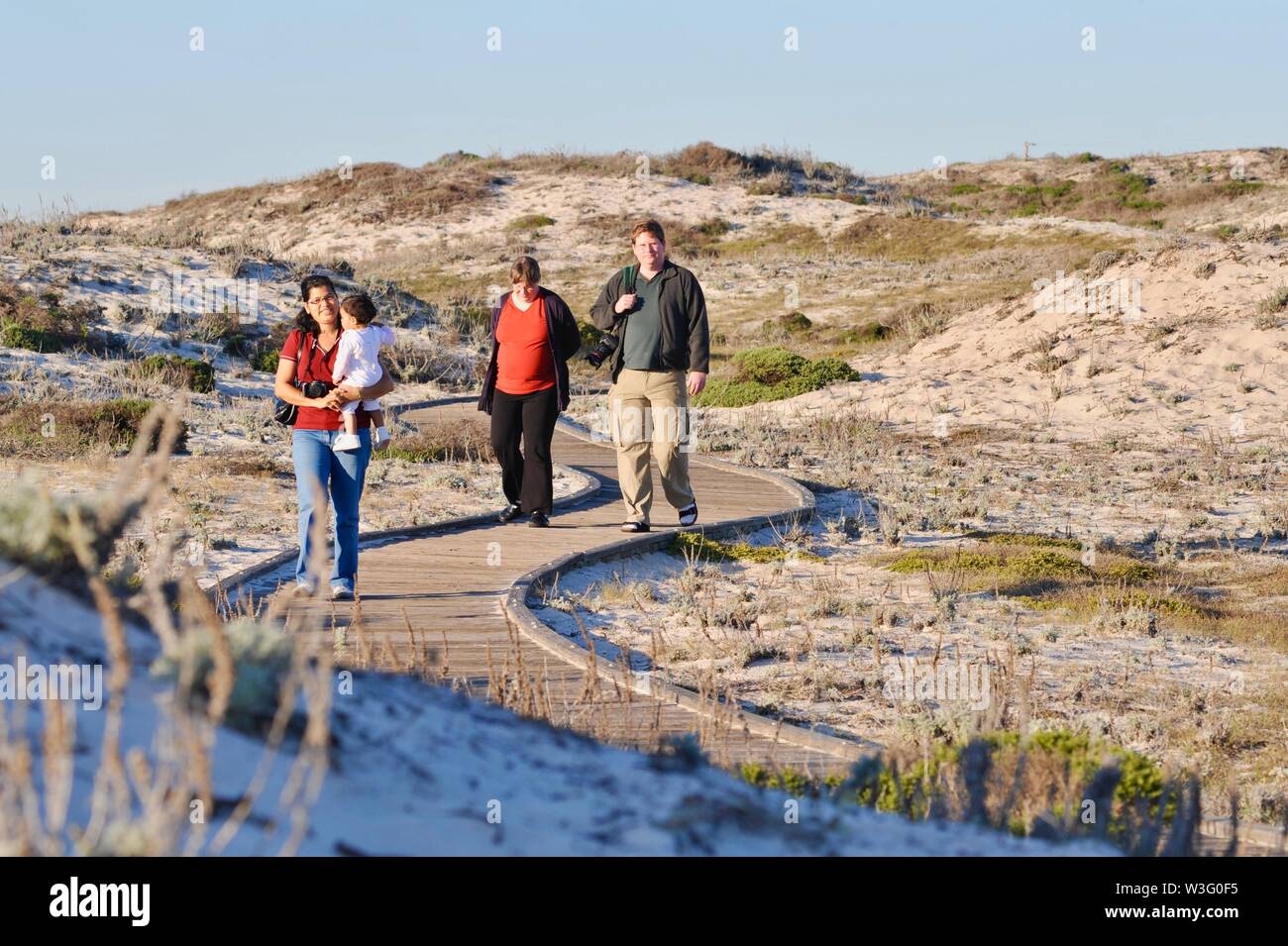 People, mother child, walking on boardwalk pathway through coastal ...