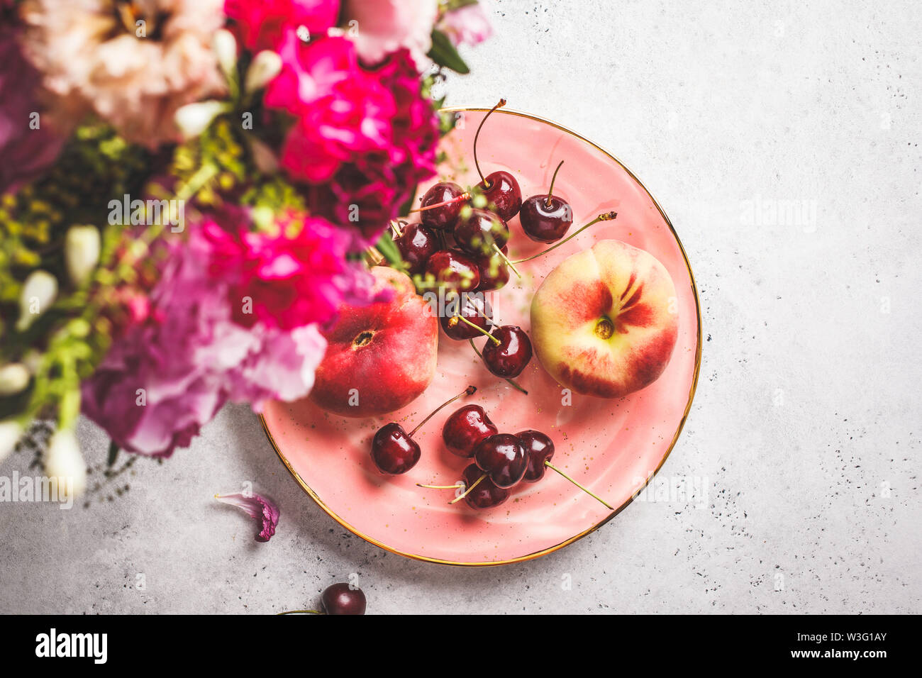 Beautiful pink food background. Flowers and berries on a pink plate ...