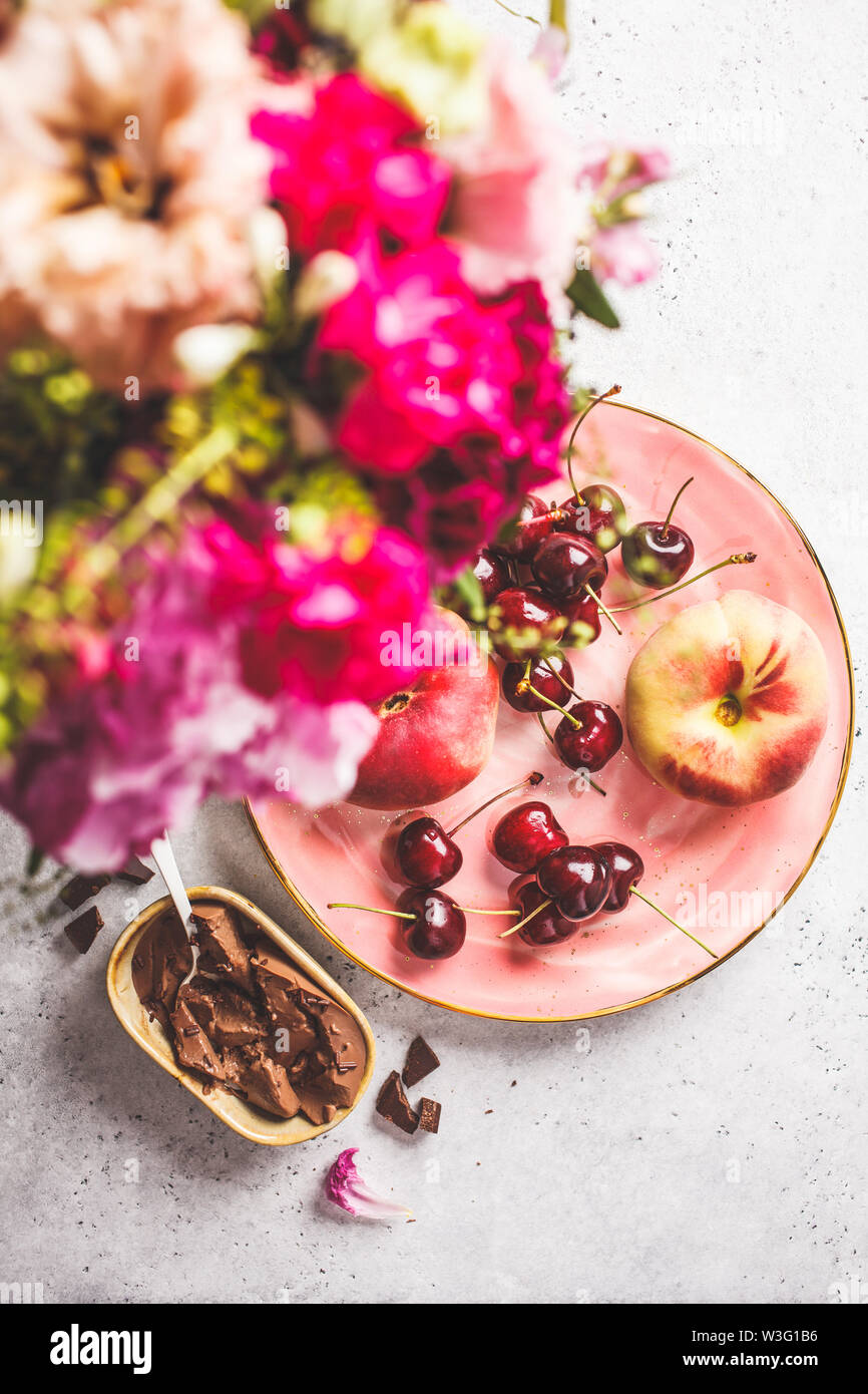 Beautiful pink food background. Flowers and berries on a pink plate ...