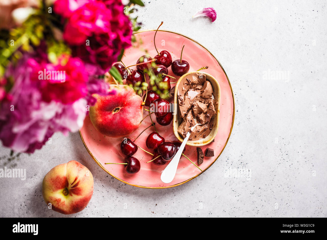 Beautiful pink food background. Flowers and berries on a pink plate ...