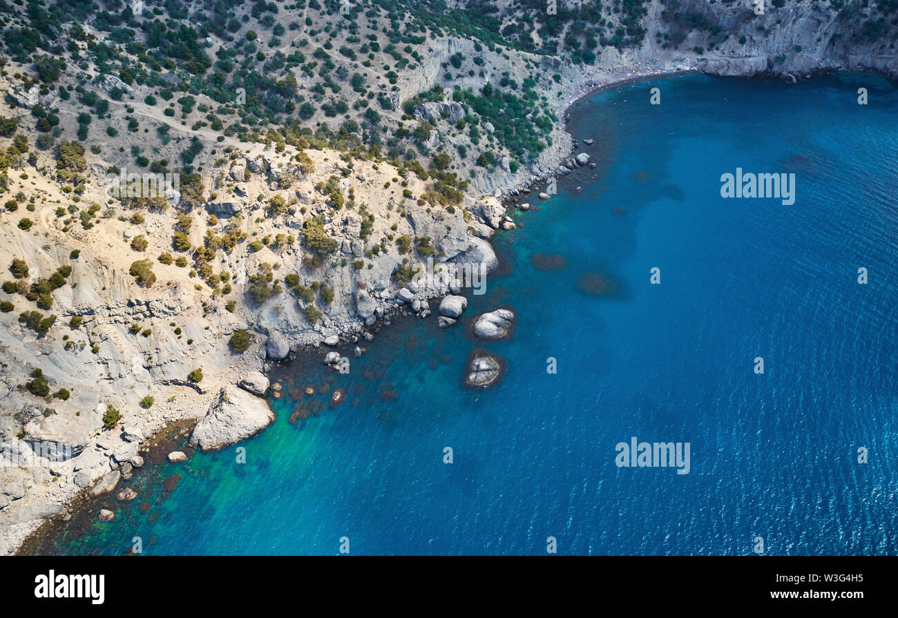 boat floats in the blue Bay at the rocks Stock Photo - Alamy