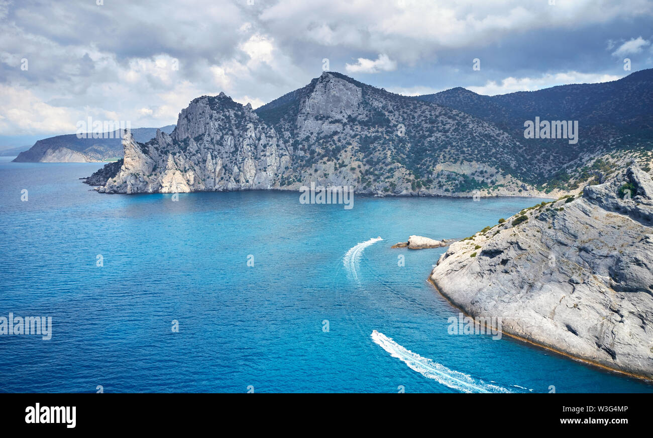 boat floats in the blue Bay at the rocks Stock Photo - Alamy