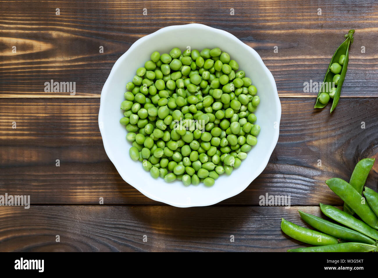 Healthy eating concept. Fresh green peas in white plate on dark wooden ...