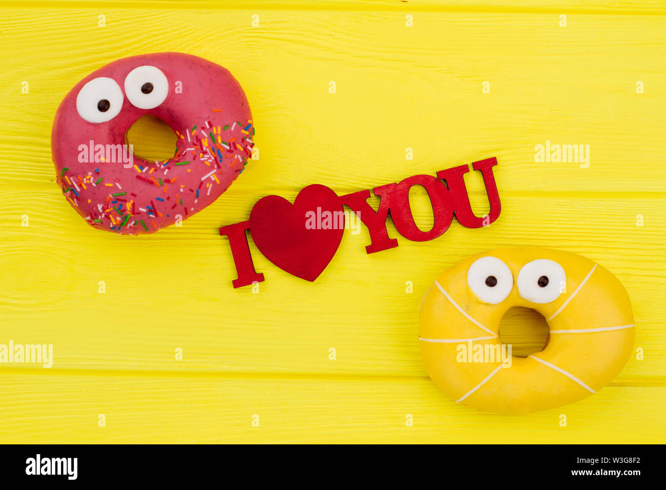 Romantic composition with donuts on yellow background Stock Photo - Alamy