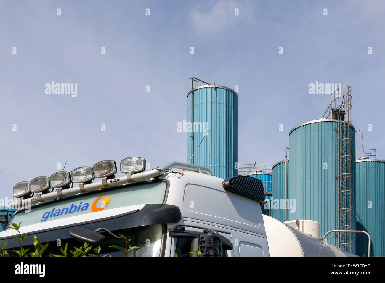 Cab of Glanbia milk tanker with Glanbia logo parked in front of silos ...