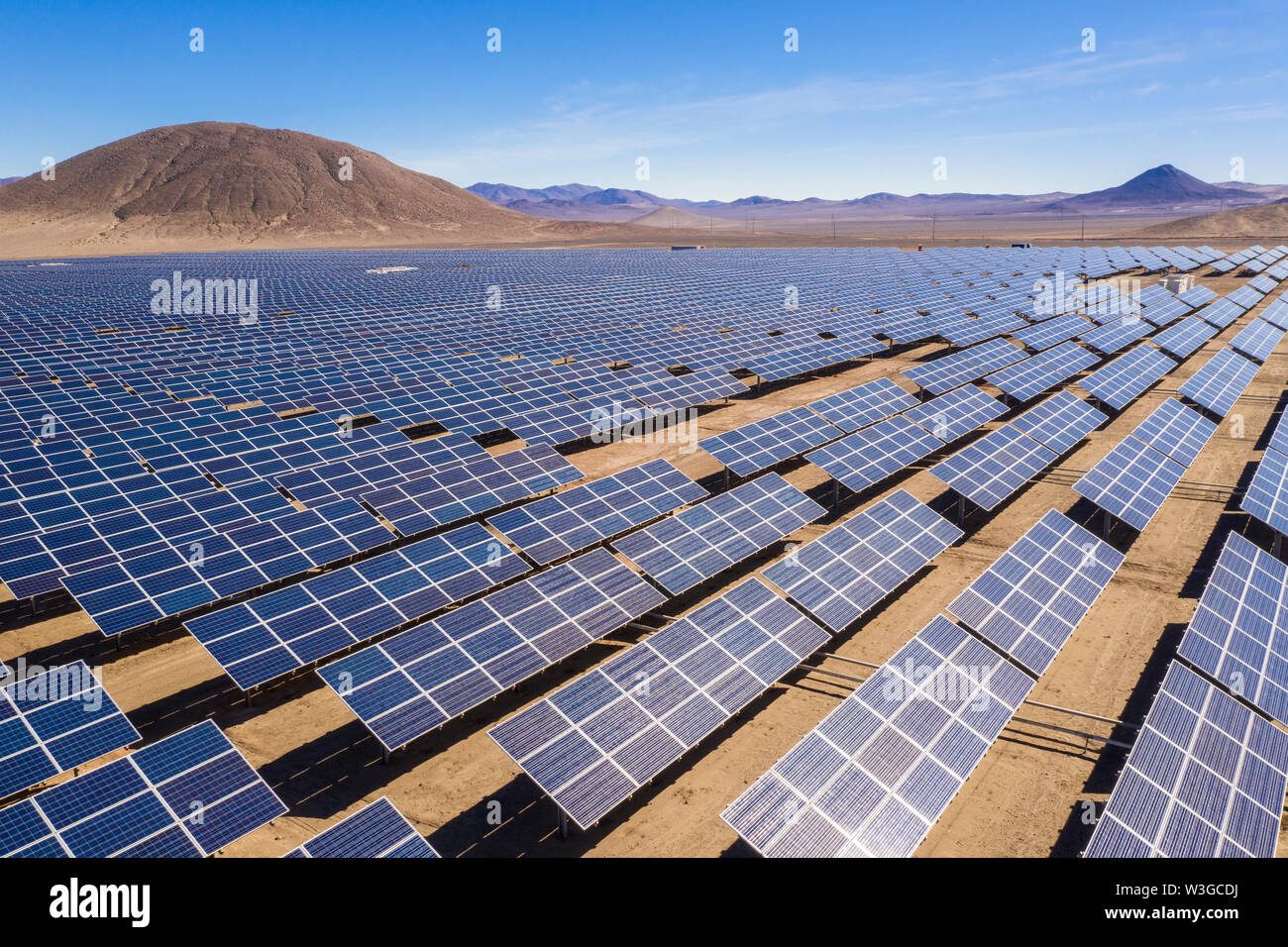 Aerial view of hundreds solar energy modules or panels rows along the dry lands at Atacama ...