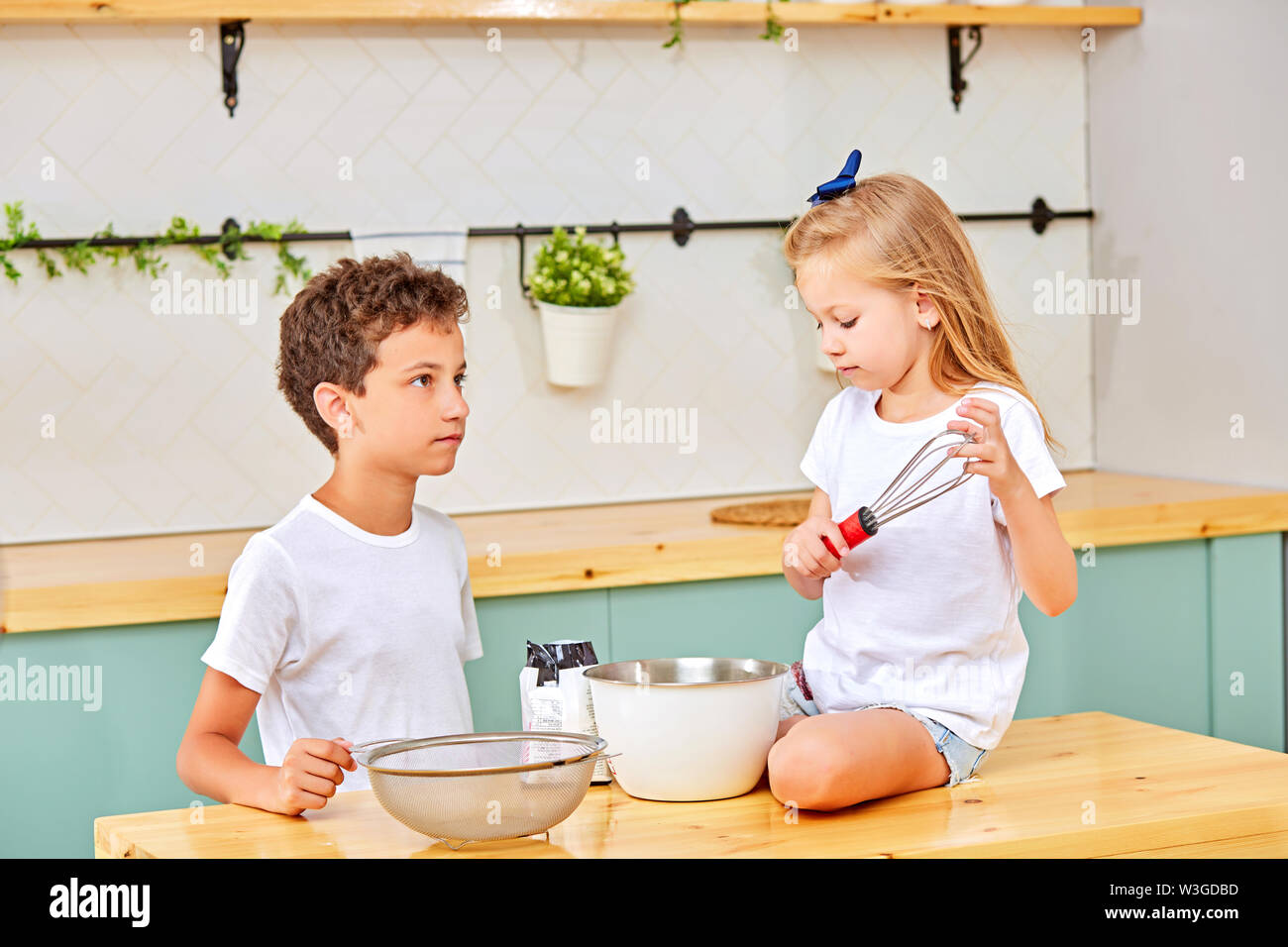 Little boy and girl mixing fresh dough for pastry in a bowl while ...