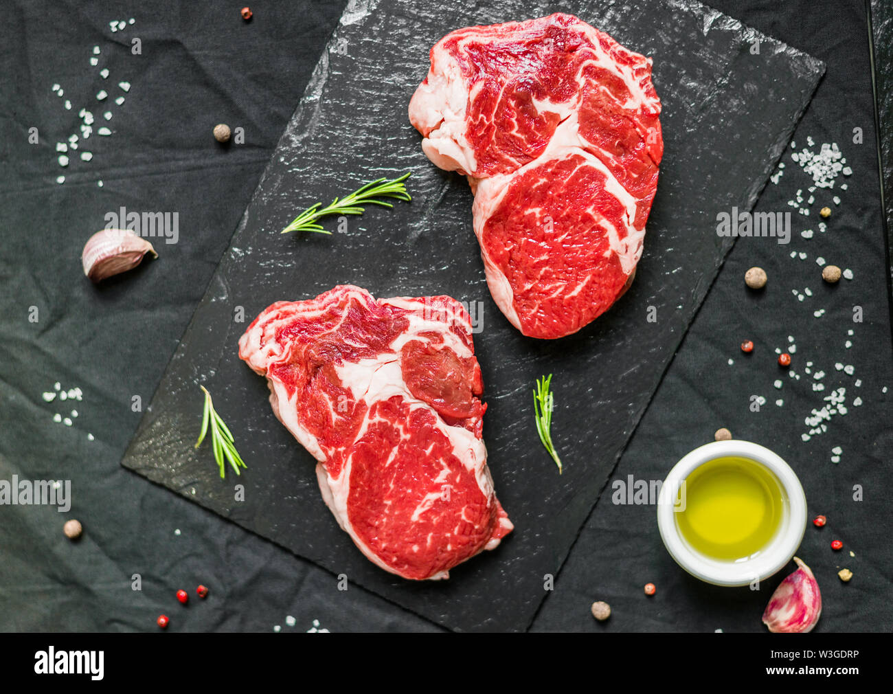 Rib eye beef cow steak meat with spices and herbs against black ...