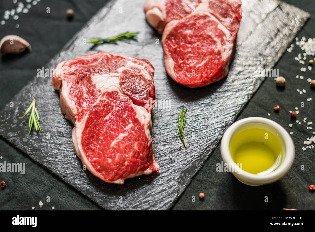 Rib eye beef cow steak meat with spices and herbs against black ...
