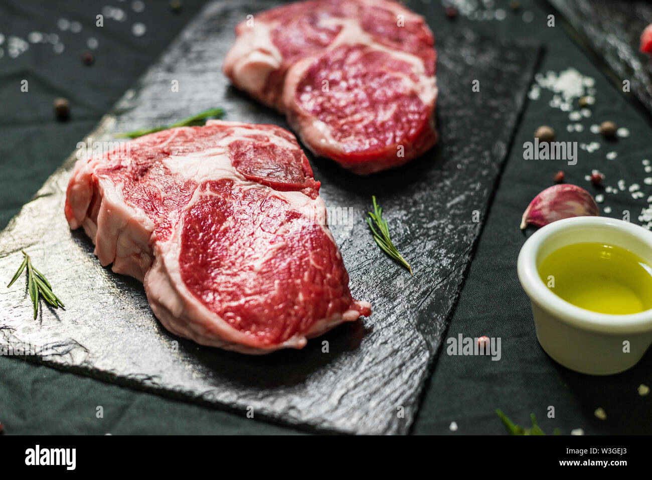 Rib eye beef cow steak meat with spices and herbs against black ...