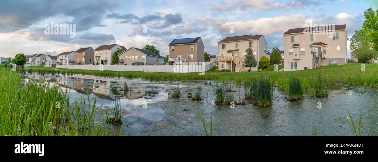Beautiful multi storey homes built in front of a grassy and shiny pond ...