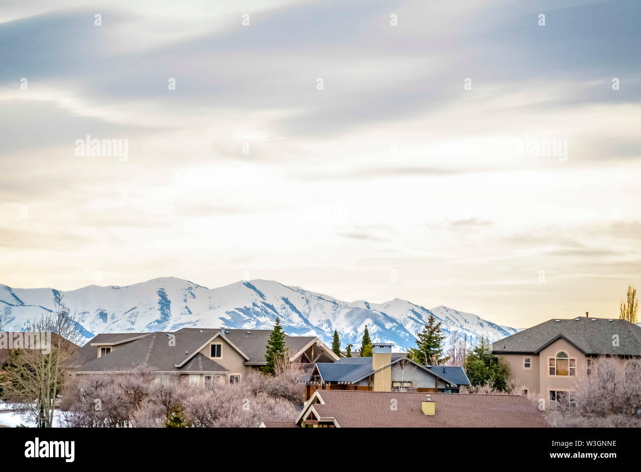 Neighborhood in winter with snow covered mountain and overcast sky ...