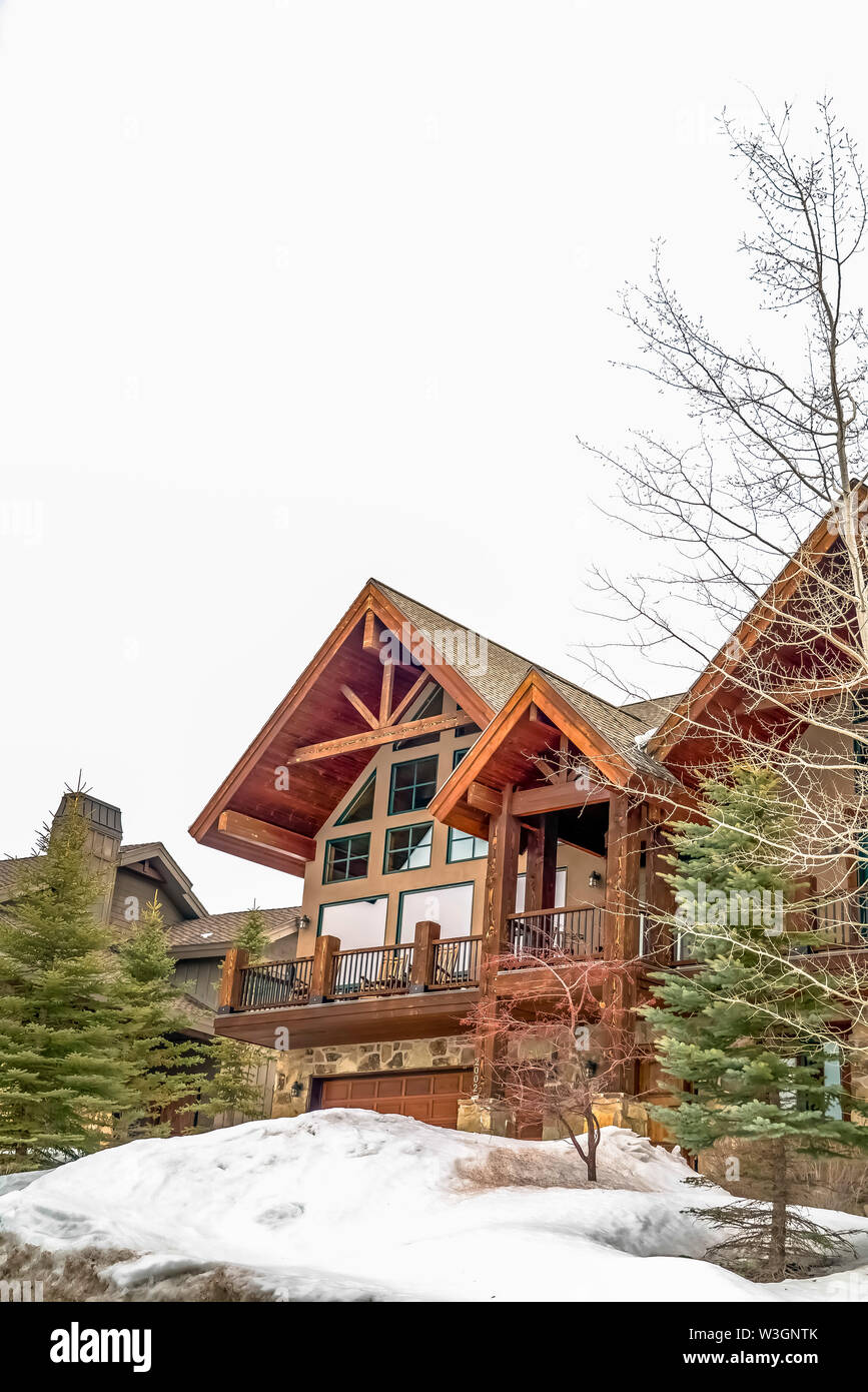 Beautiful house exterior surrounded by snow y ground and conifers in ...