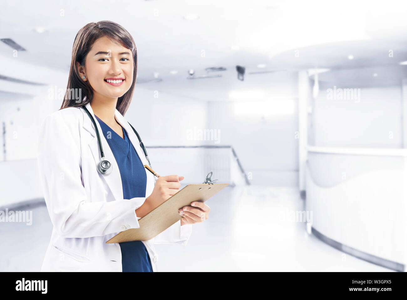 Asian woman doctor in white lab coat and stethoscope holding clipboard ...