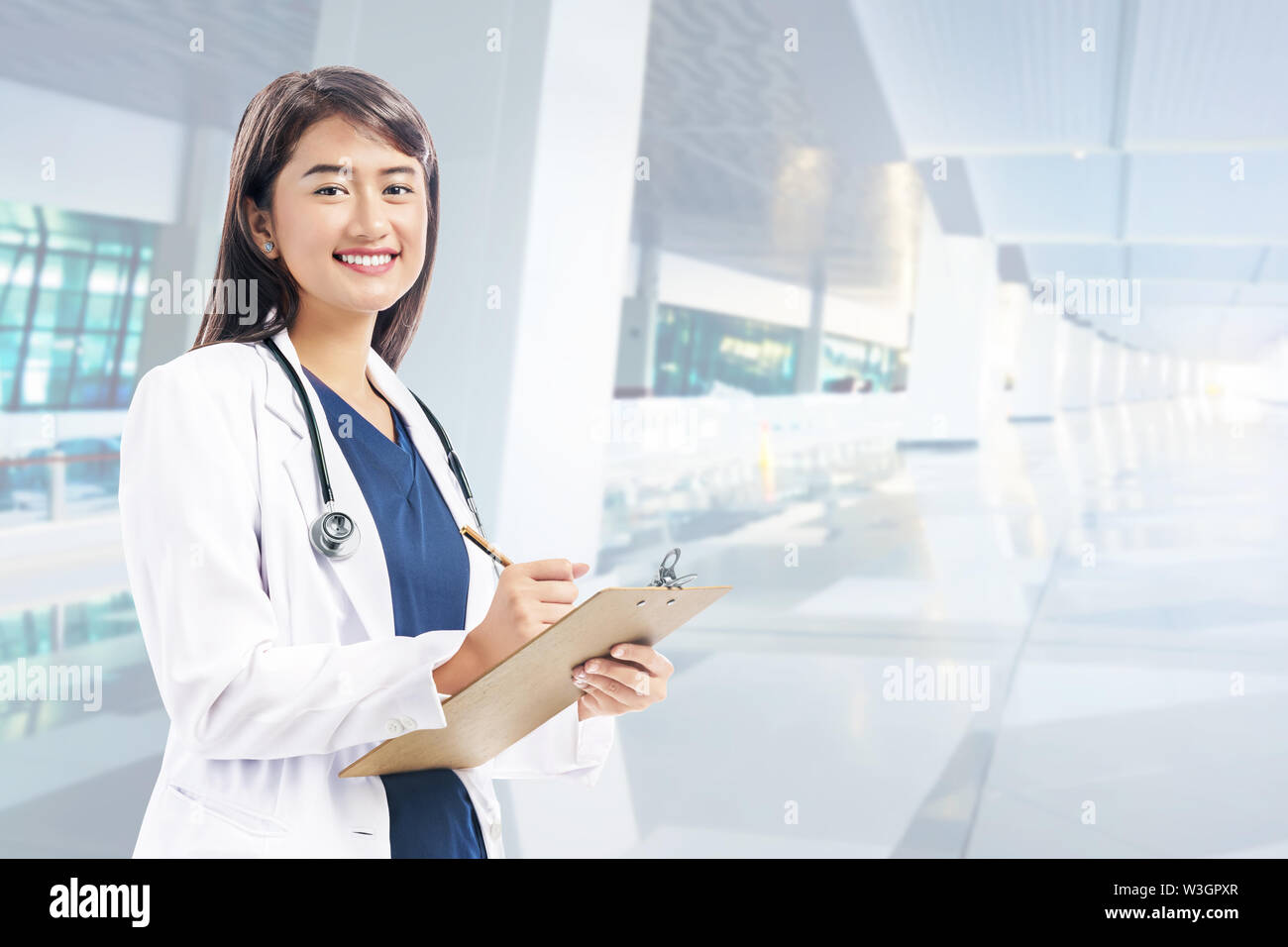 Asian woman doctor in white lab coat and stethoscope holding clipboard ...