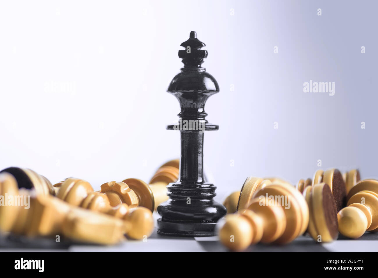 Wooden chess piece defeated by black king chess piece on the chessboard ...