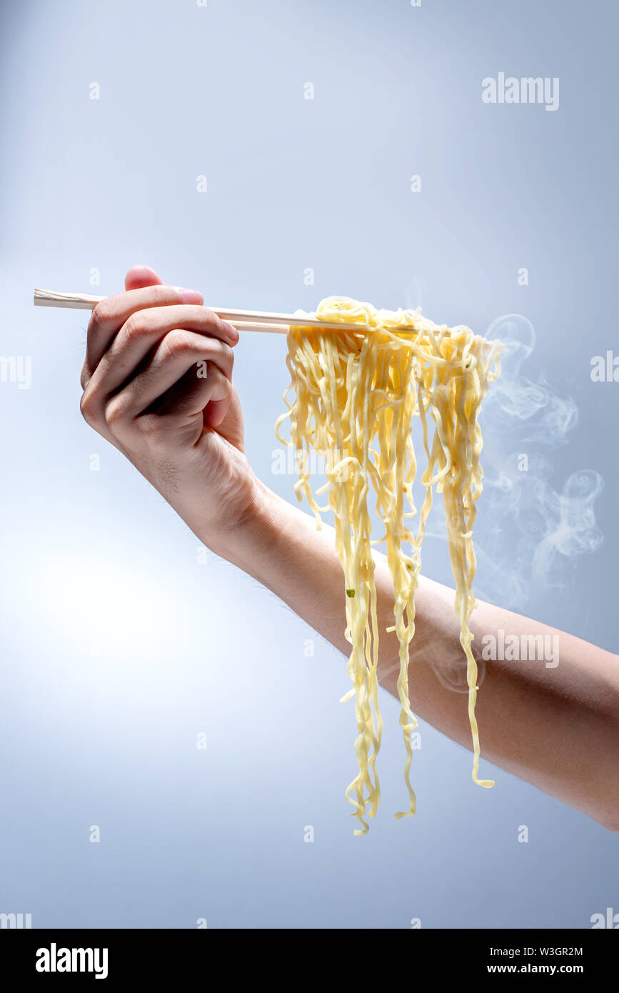 People eat the noodles with chopsticks over bright background Stock ...