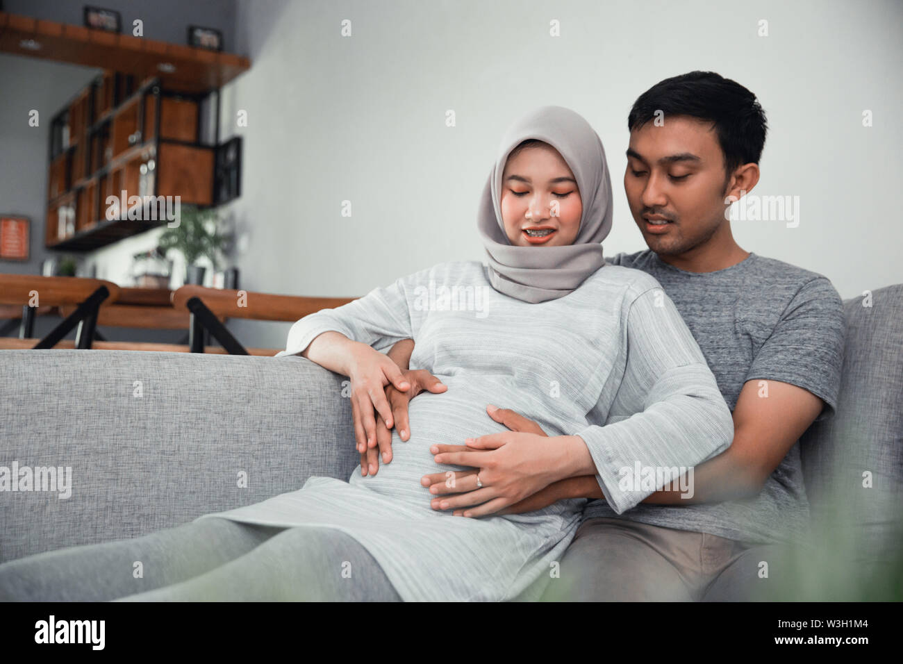 gesture of couple's hand hold on pregnant belly when sitting on the ...