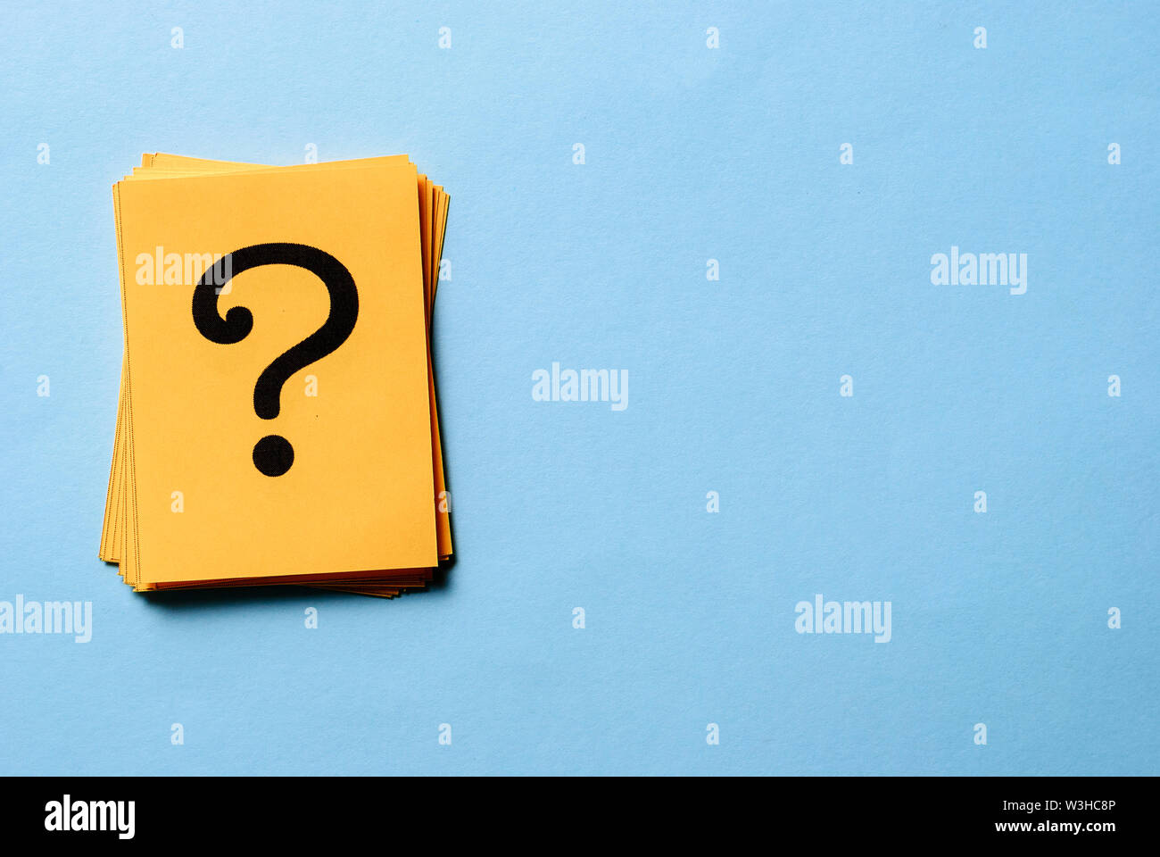 Stack of question marks on yellow cards arranged to the side on blue ...