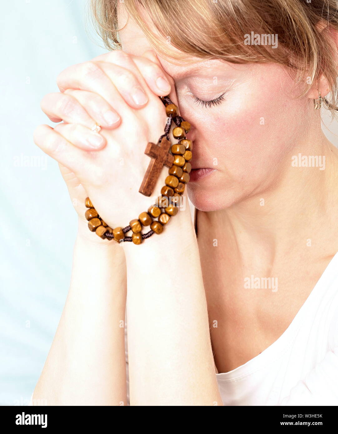 woman praying to God with holy cross in her hands with white background ...