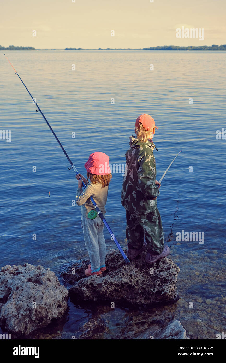 Two kids boy and girl fishing in a Volga river on a stone coast. View ...