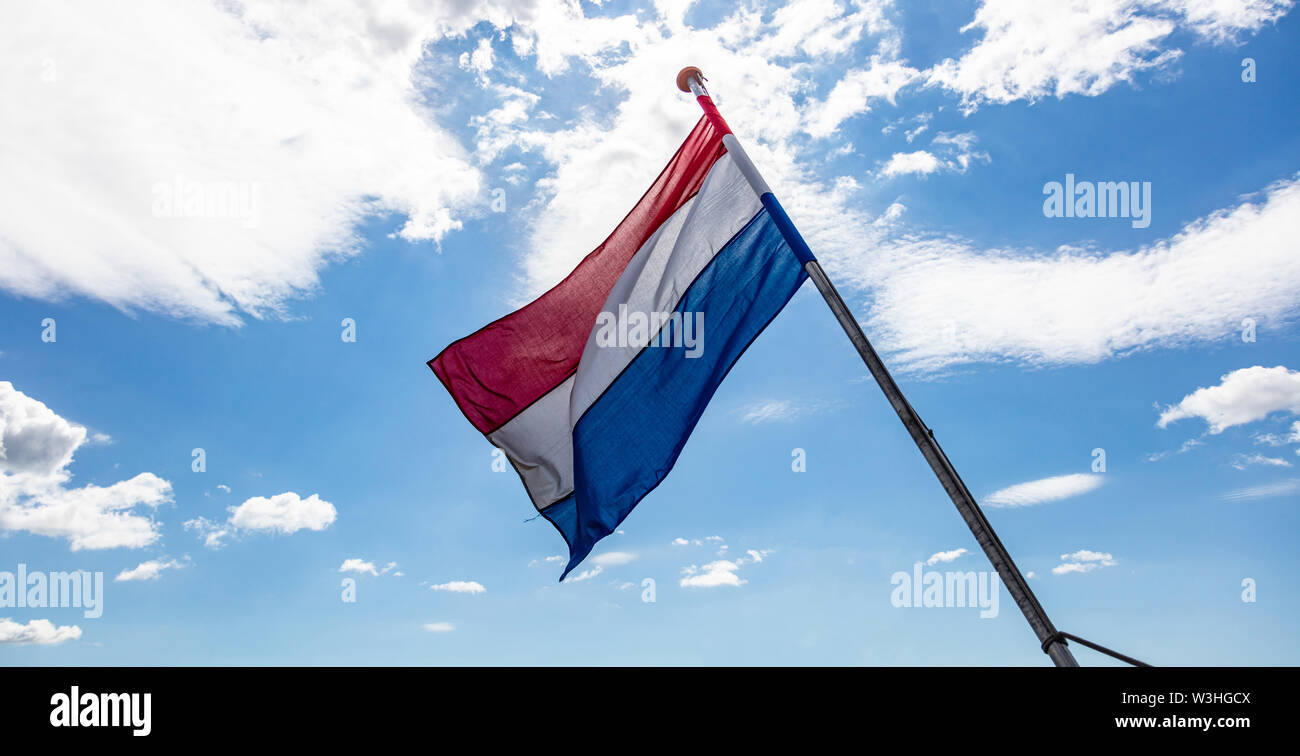 Netherlands flag. Dutch national symbol waving on pole against blue sky ...