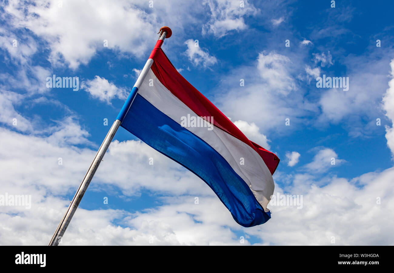 Netherlands flag. Dutch national symbol waving on pole against blue sky ...