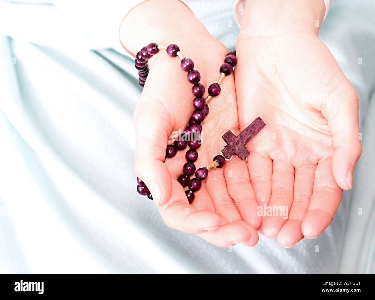 woman praying hand together reaching out with a crucifix and rosary ...