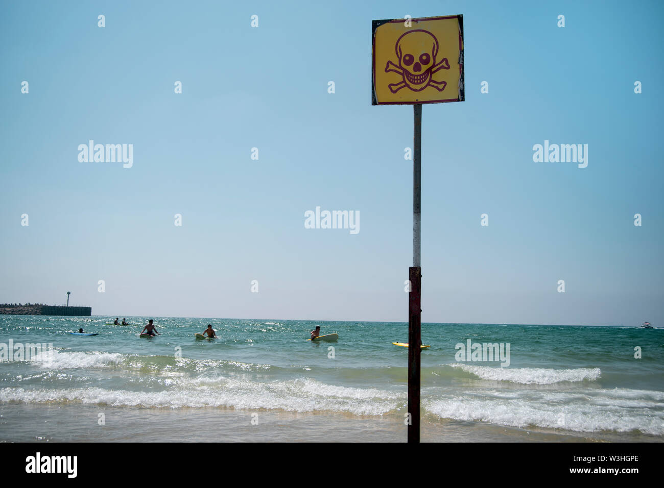 People swimming in the ocean behind a warning sign Stock Photo - Alamy