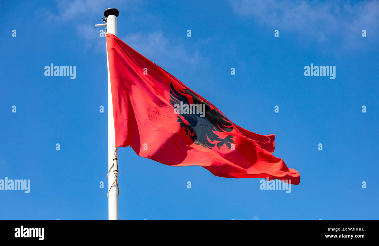 Albania flag, Albanian national symbol waving against clear blue sky ...