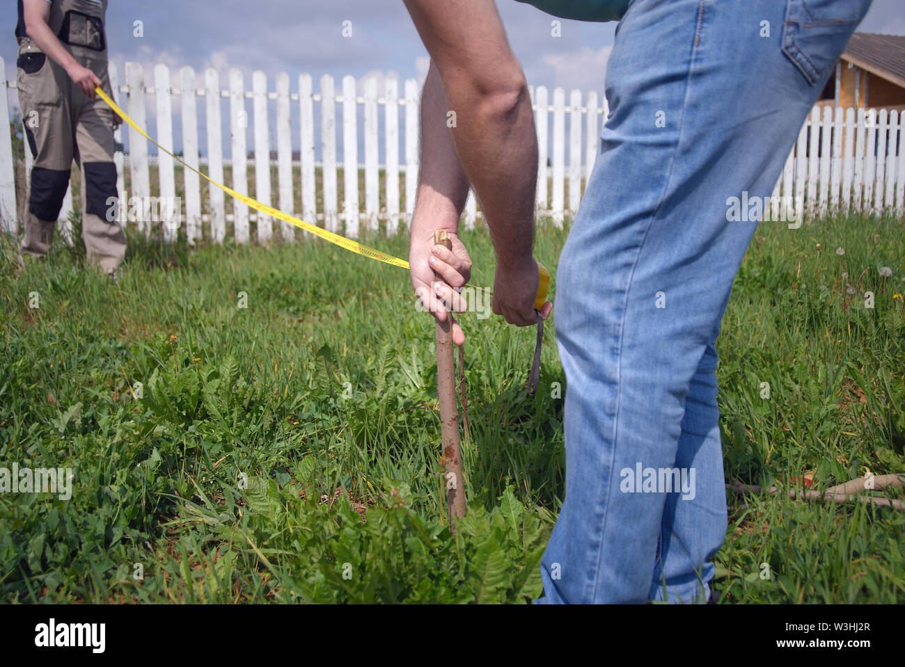 Two workers arranging a boundary with a ruler an wooden stick, the ...