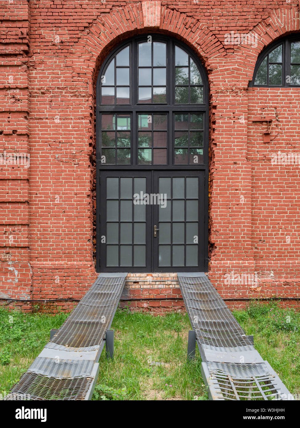 French arched window in an old red brick wall with metal rail rails ...