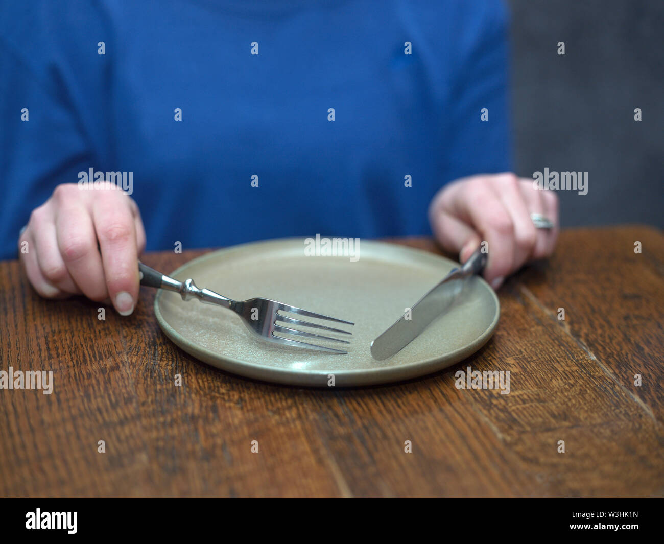 A woman sitting at the dinner table waiting for food, shallow depth of ...