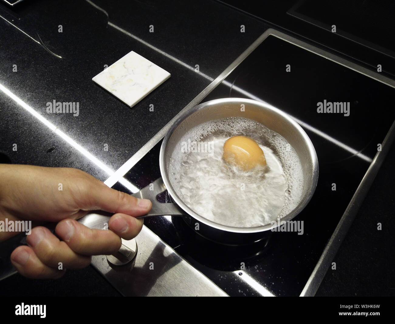 Closeup of a hand holding a casserole with egg in boiling water Stock ...