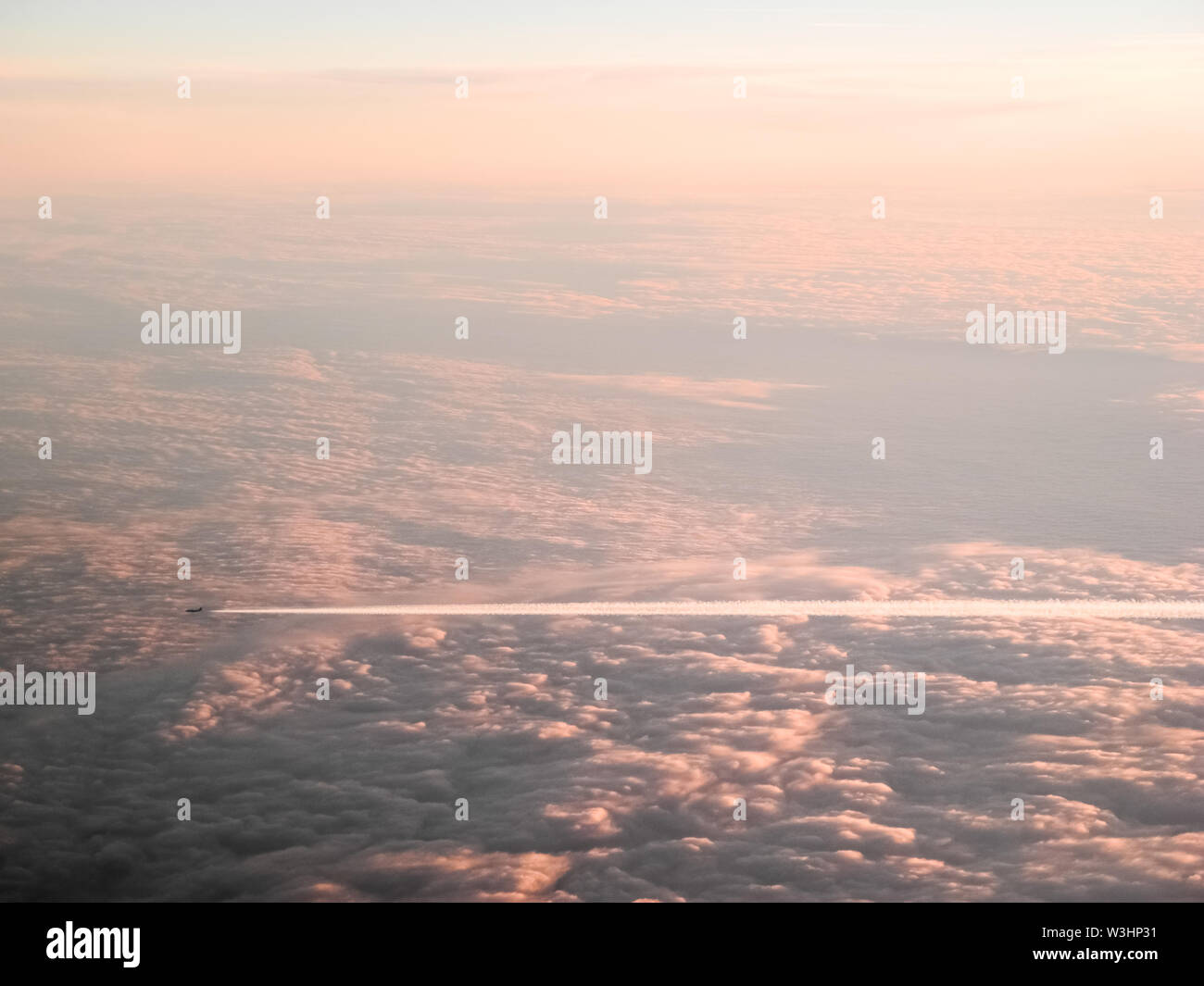 Aerial view from aircraft of sunset and clouds with aircraft trail or ...