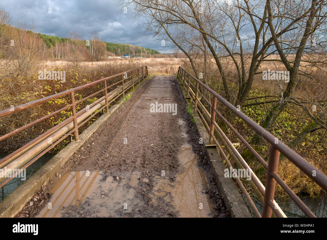 Pedestrian bridge over the river with traces of tread machines on an ...