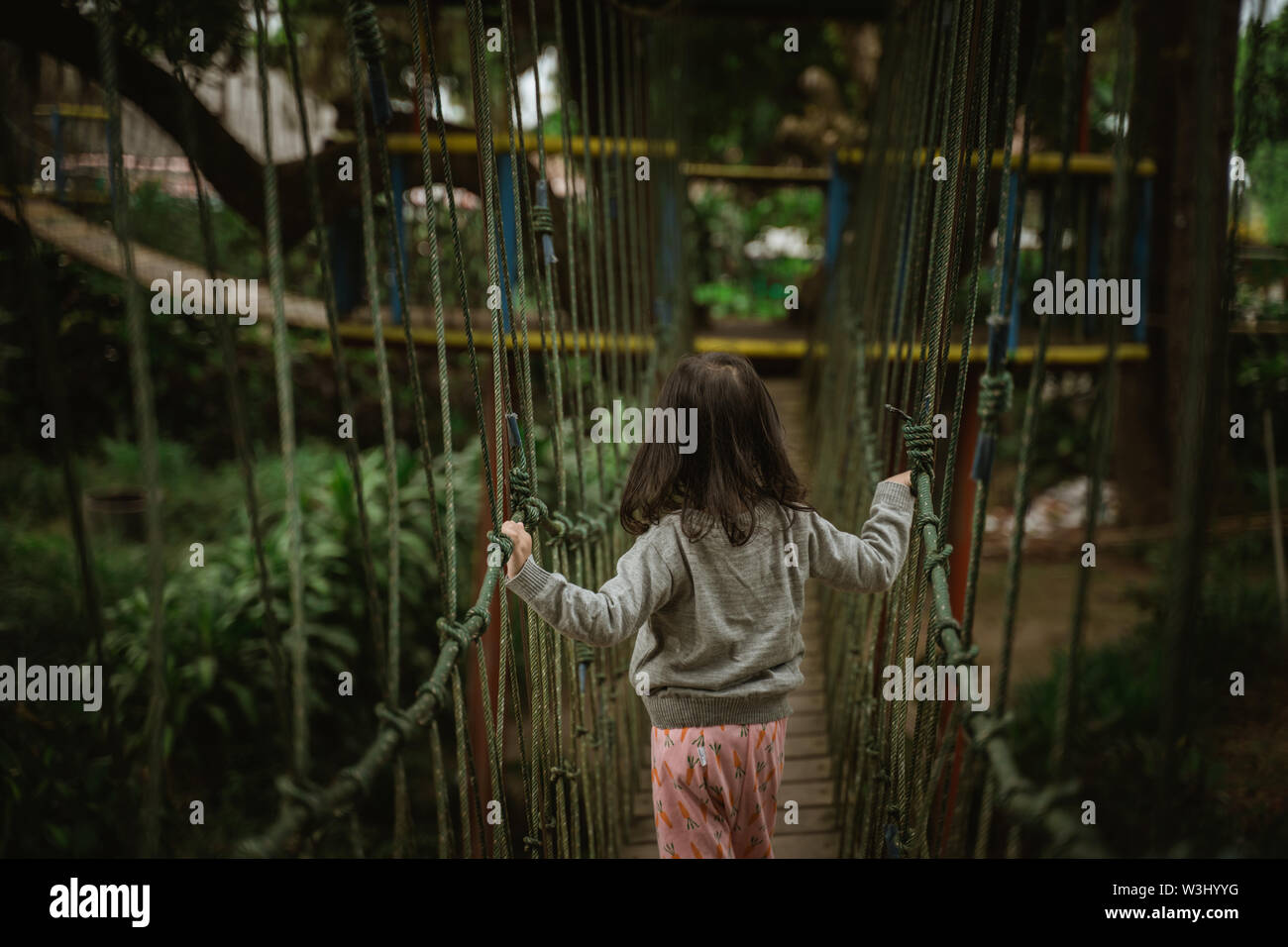 young asian kid playing on outdoor playground in nature crossing ...