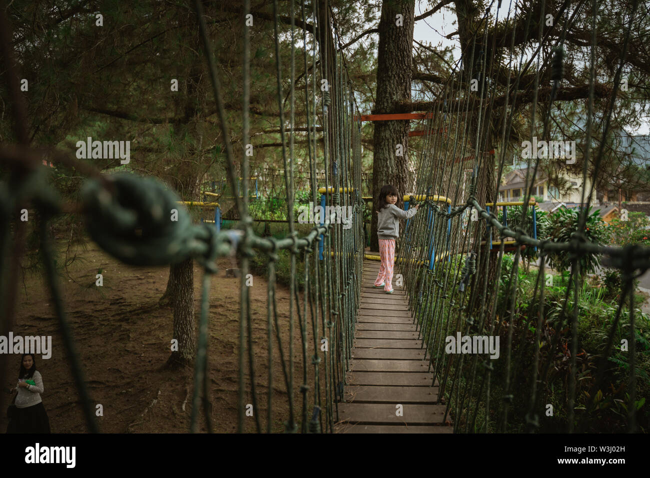 young asian kid playing on outdoor playground in nature crossing ...