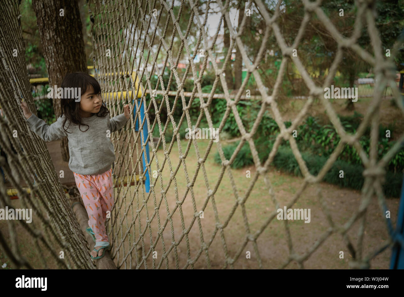 young asian kid playing on outdoor playground in nature crossing ...
