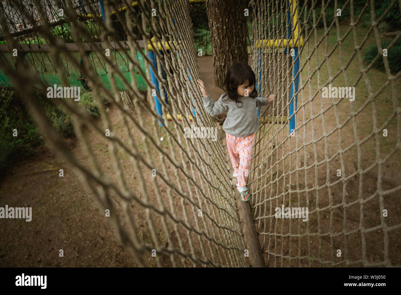 young asian kid playing on outdoor playground in nature crossing ...