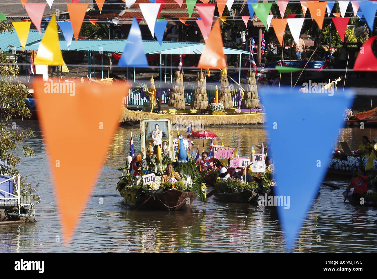 Ayutthaya, Thailand. 16th July, 2019. Boats carrying wax castle move along a canal to take part ...