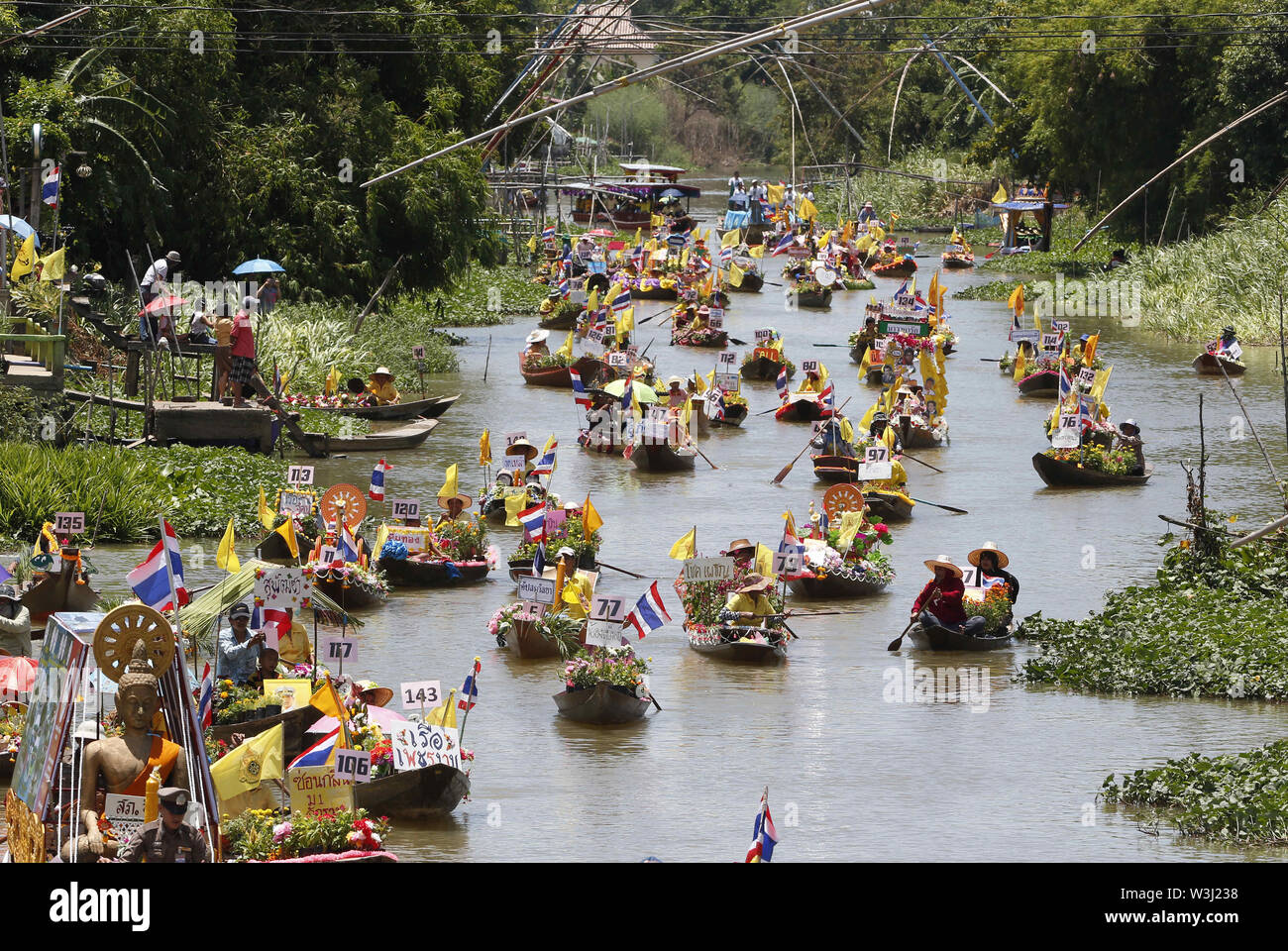 Ayutthaya, Thailand. 16th July, 2019. Boats carrying wax castle move along a canal to take part ...