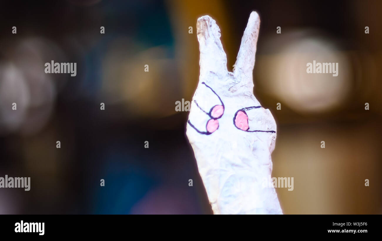 Hand showing peace gesture through torn yellow paper background ...