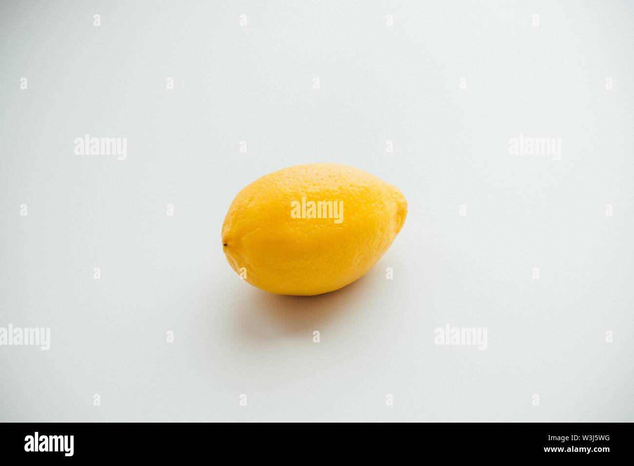 Single isolated yellow fresh lemon on a white surface and white ...