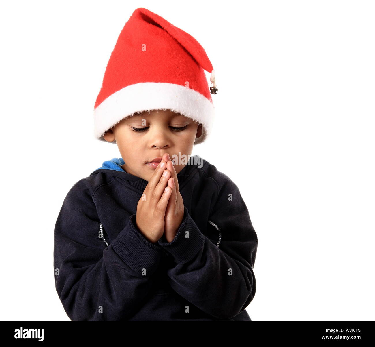 little boy praying at Christmas with Christmas hat on white background ...