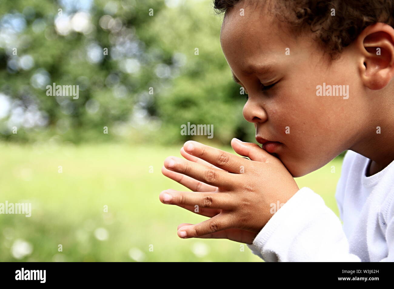 little boy praying to God and being religious stock image with hands ...
