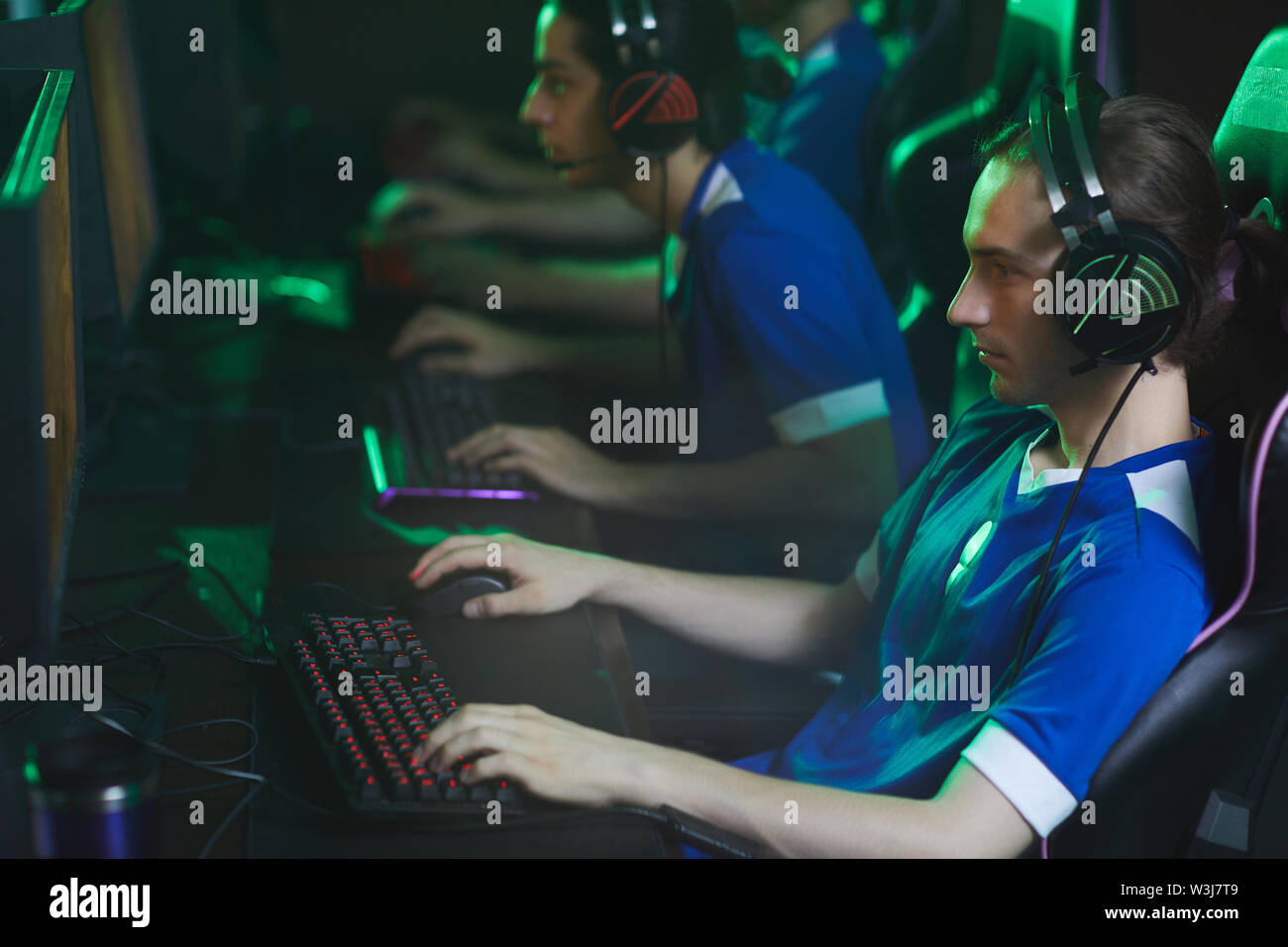 Young focused cyber gamer in headset sitting in gaming chair and using ...